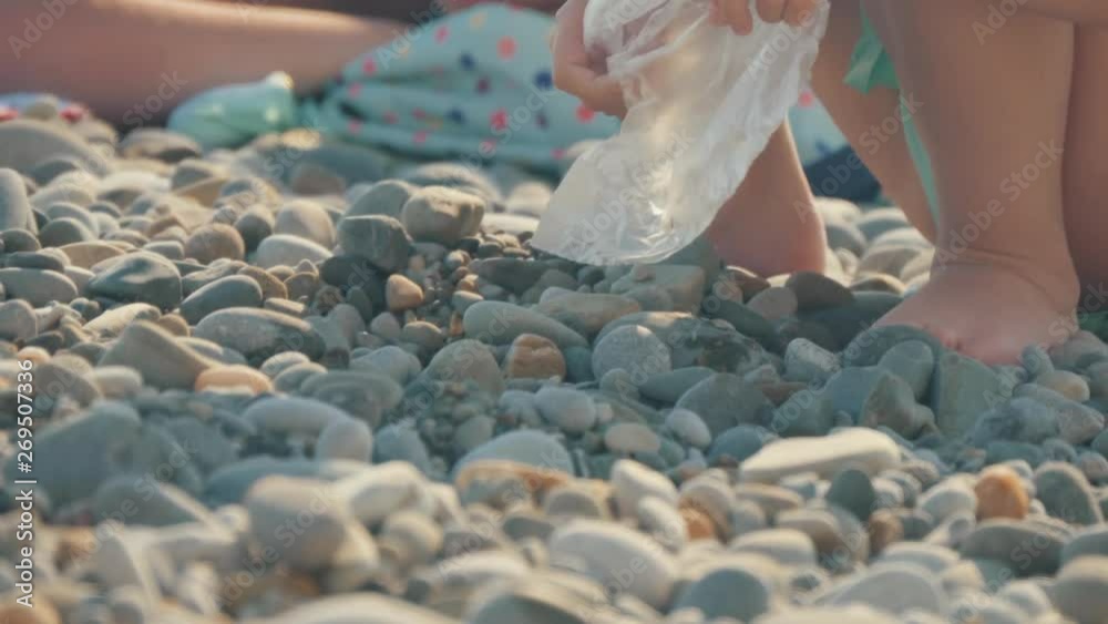 A child on the coast playing with pebbles.The hands of children gather ...