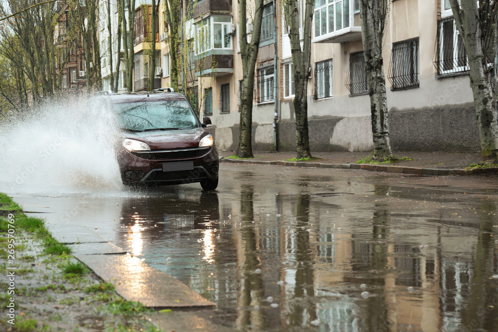 Car driving through large puddle outdoors on rainy day Stock Photo ...