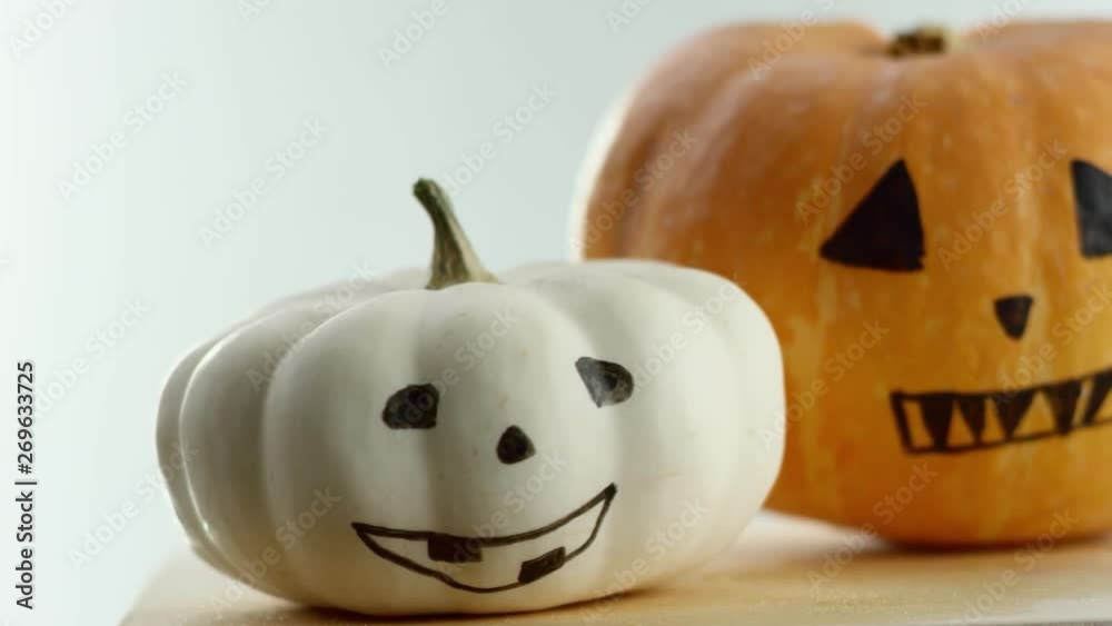 video shows two painted pumpkins, white background, camera goes from ...