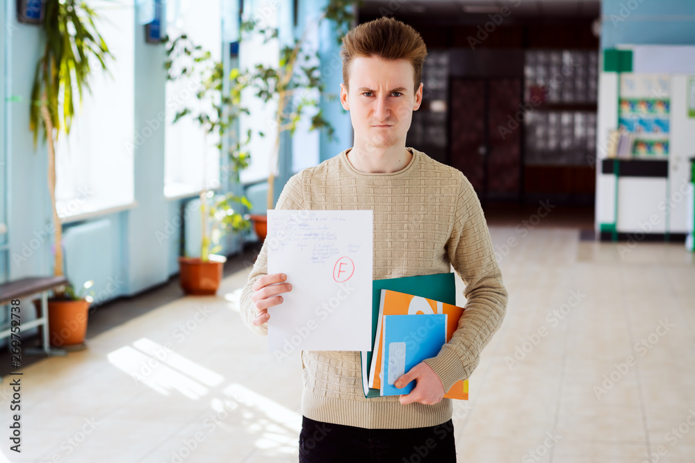 Angry and baffled male student with poor results of exam in corridor ...