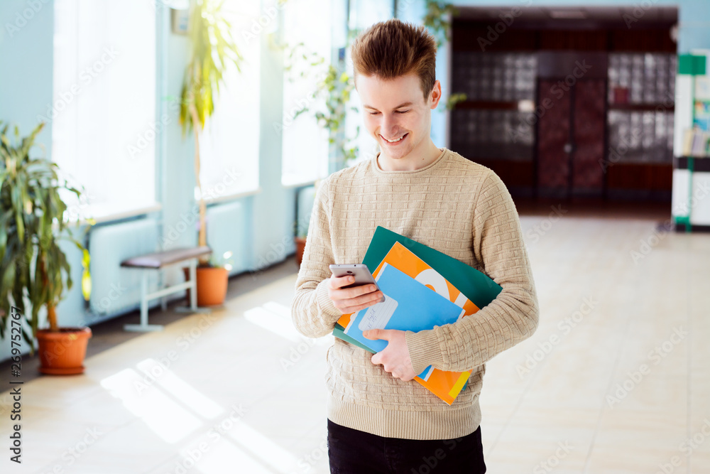 Cheerful caucasian student with smartphone and course books standing in ...