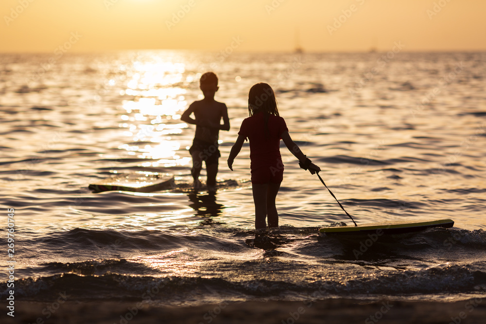 Happy children playing on the beach at the sunset time. Concept of ...