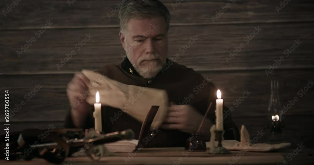 A confederate officer takes off his gloves and writes in a journal ...