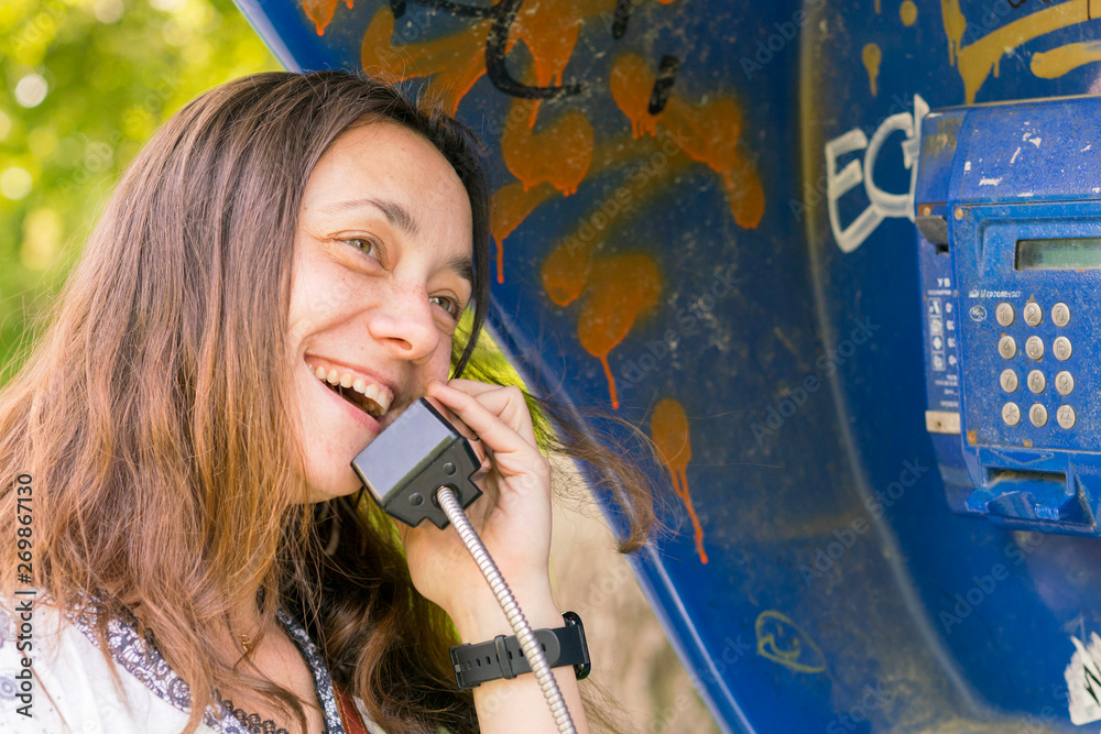 Beautiful young girl in a phone booth. The girl is talking on the phone ...