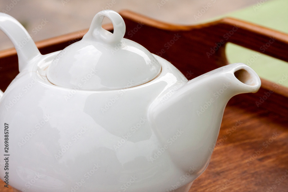 An elegant simple plain white english teapot on an organic wooden tray ...