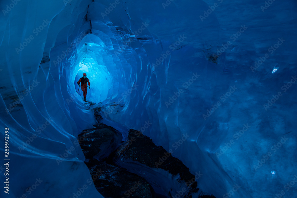 Guide inside an ice cave on a glacier in Alaska. Glacier caves are rare ...