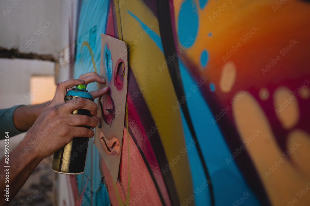 Graffiti artist spray painting on card board at alley Stock Photo ...