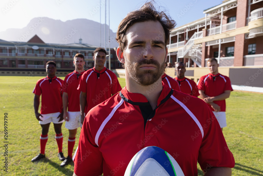 Team of male rugby players standing with rugby ball in the rugby ground ...