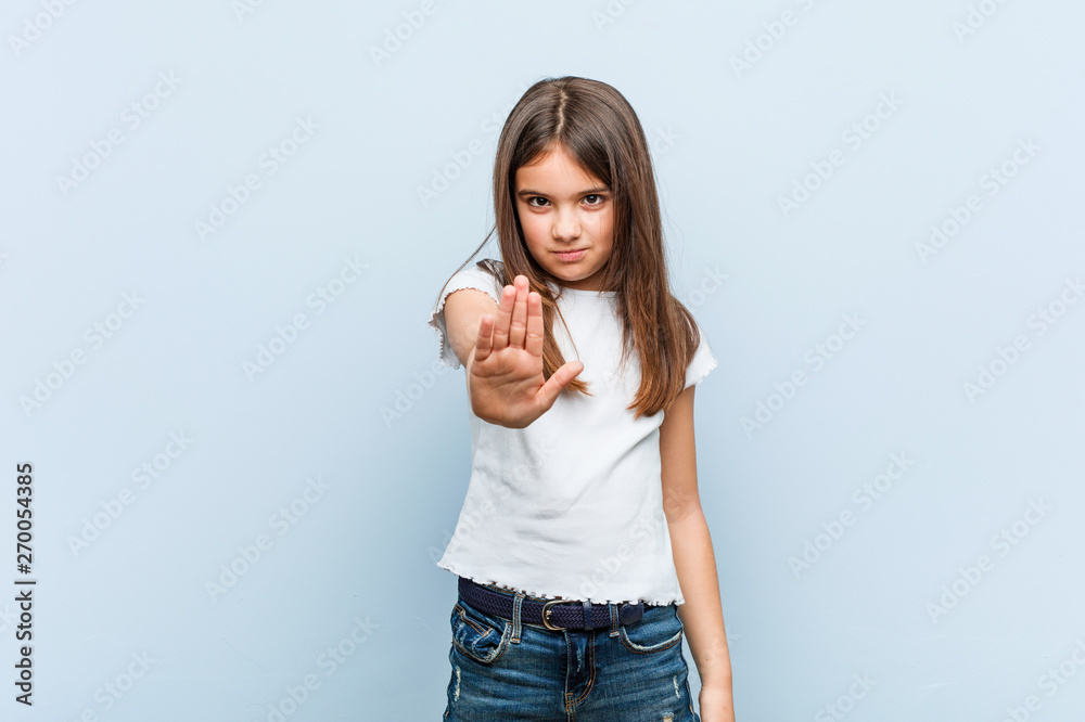 Cute girl standing with outstretched hand showing stop sign, preventing ...