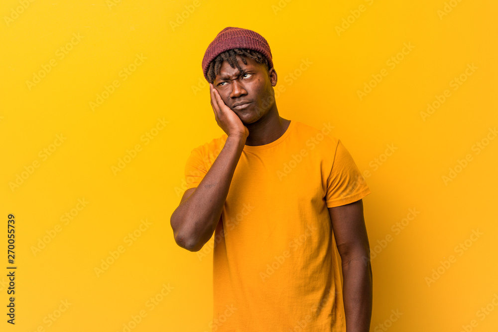 Young black man wearing rastas over yellow background who is bored ...
