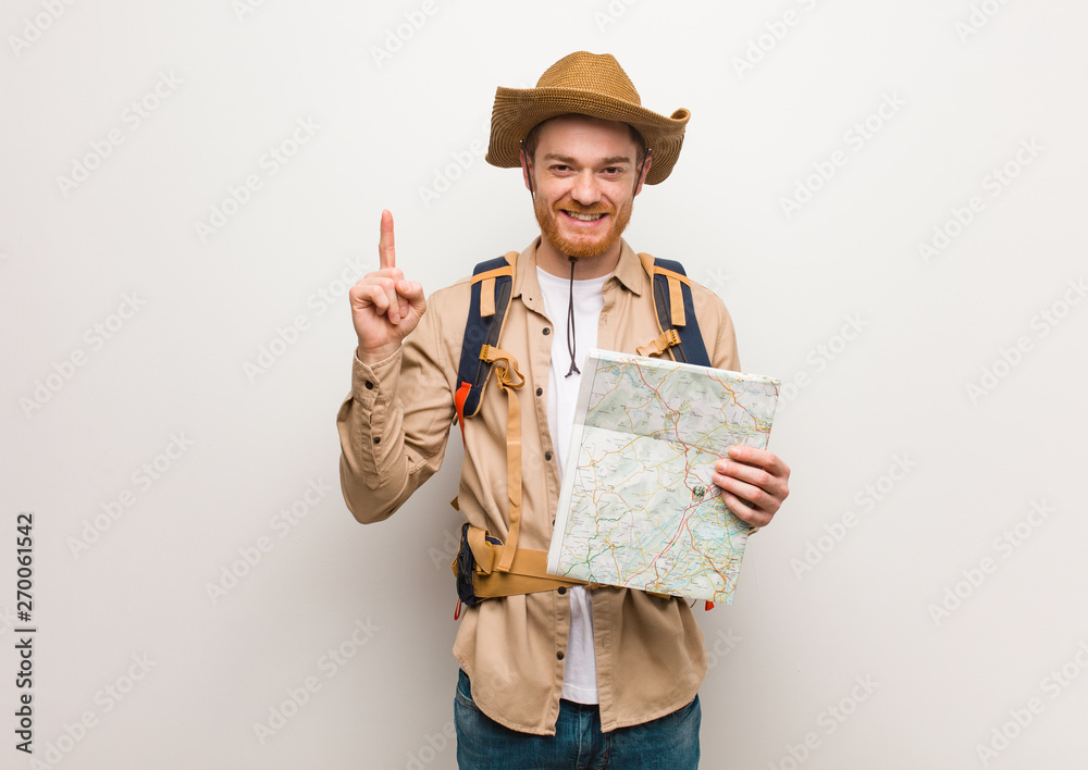 Young redhead explorer man showing number one. Holding a map. Stock ...