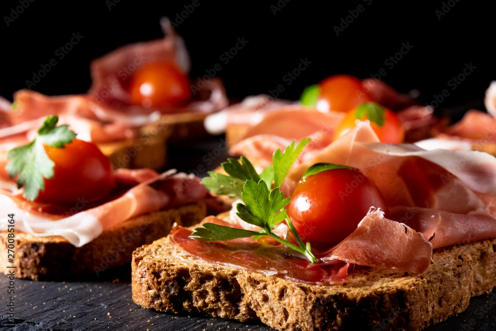 Foto de jamón serrano sobre pan tostado con tomate cherry y perejil, en ...