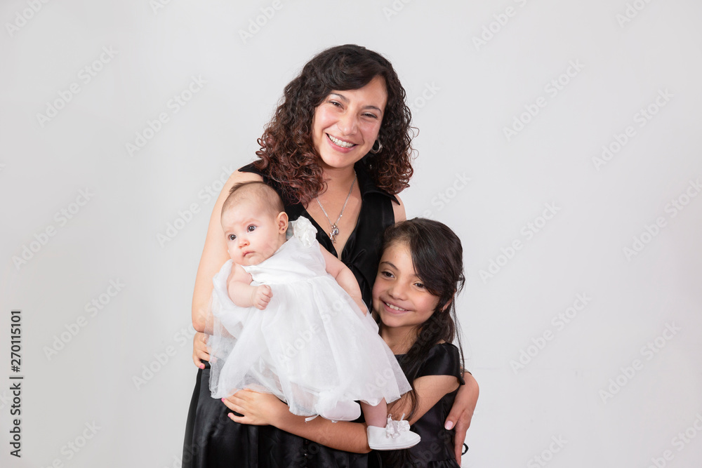 Beautiful latina mom with her two pretty daughters standing and hugging ...