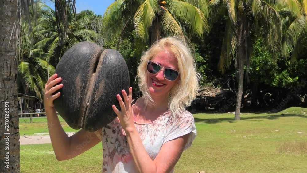 Happy tourist woman holding a female Lodoicea Maldivica nut known as ...
