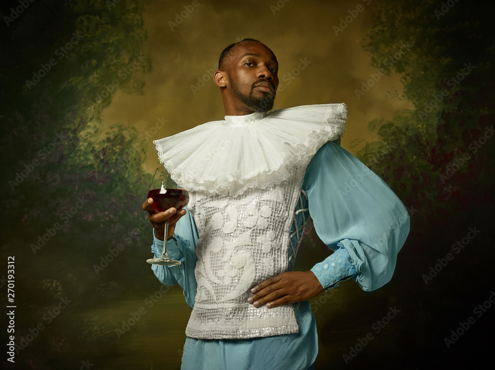 Young man as a medieval grandee or nobleman on dark studio background ...