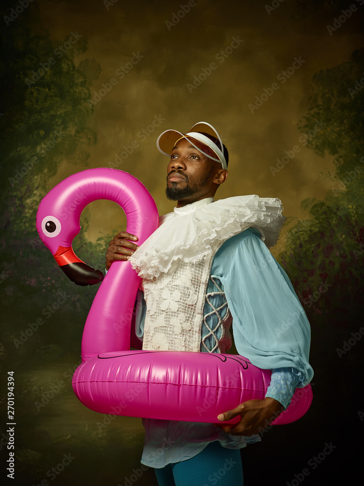 Young man as a medieval grandee or nobleman in a swimring as a pink ...