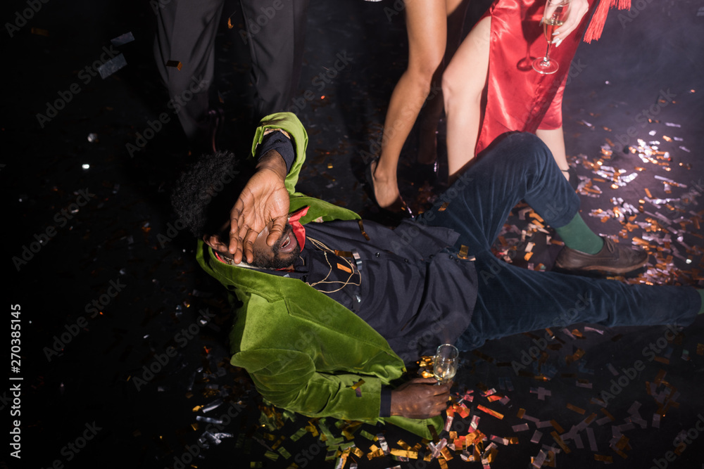 Foto de drunk african american man covering face while lying on floor ...