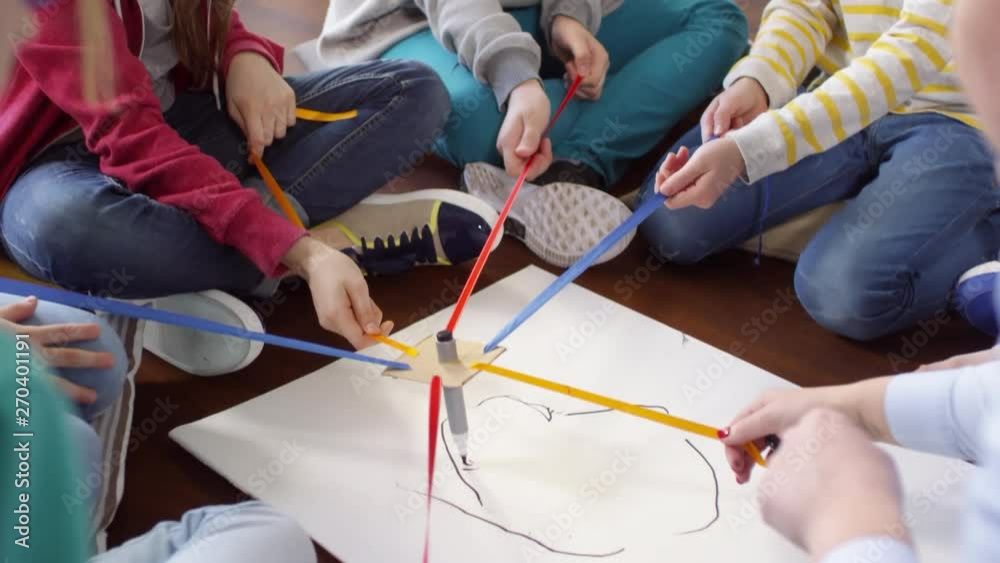Tilting shot of group of kids sitting on floor together in circle and ...