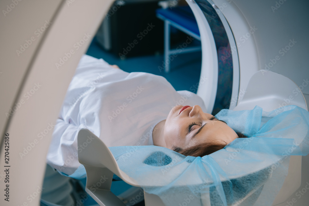 young woman lying on ct scanner bed during tomography diagnostics in ...