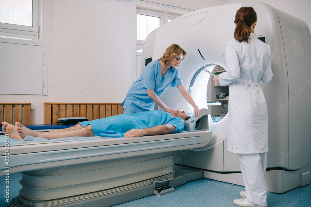 radiologist in white coat standing near ct scanner while nurse ...