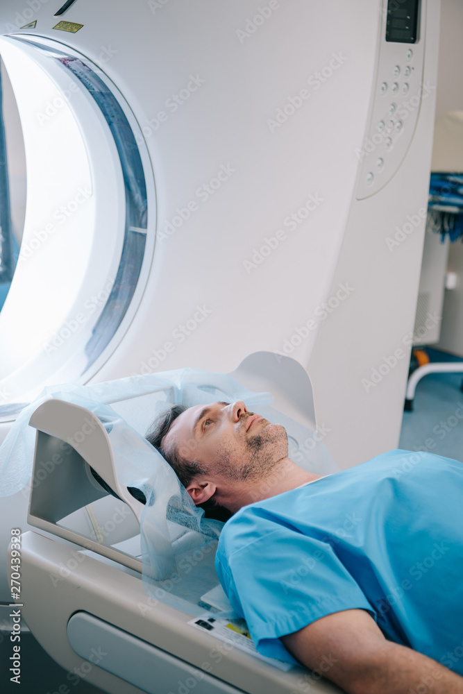 handsome man lying on ct scanner bed while having tomography test ...