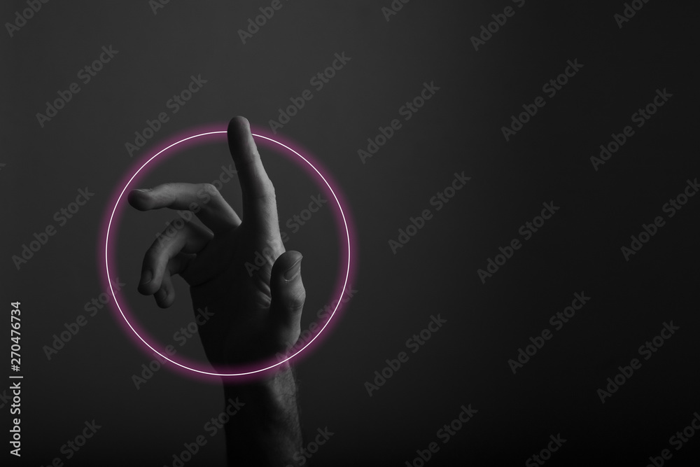 Hand pointing a finger against a dark background with abstract neon ...
