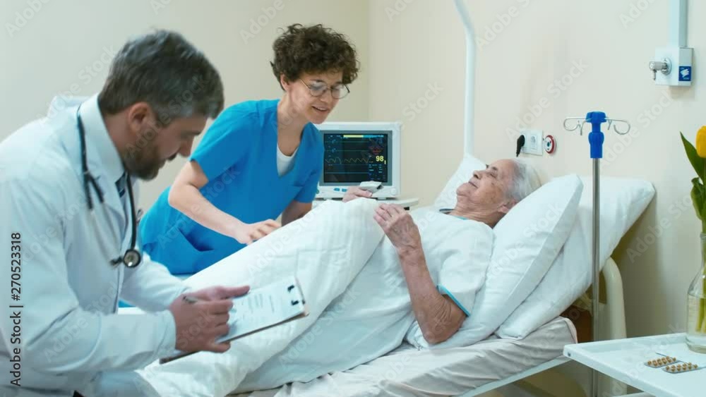 Nurse covering old woman who laying on hospital bed with blanket and ...