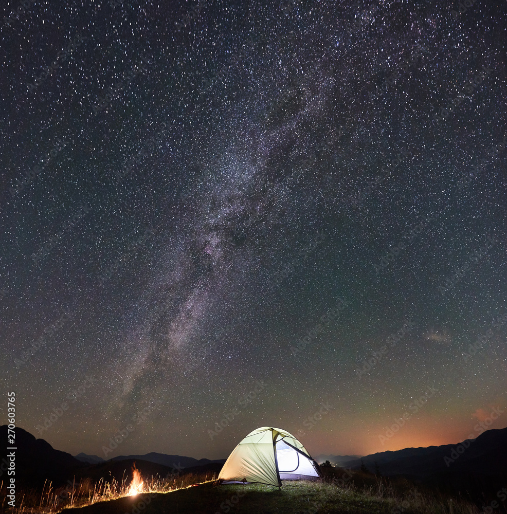 Panoramic view of tourist camping at night in the mountains. Glowing ...