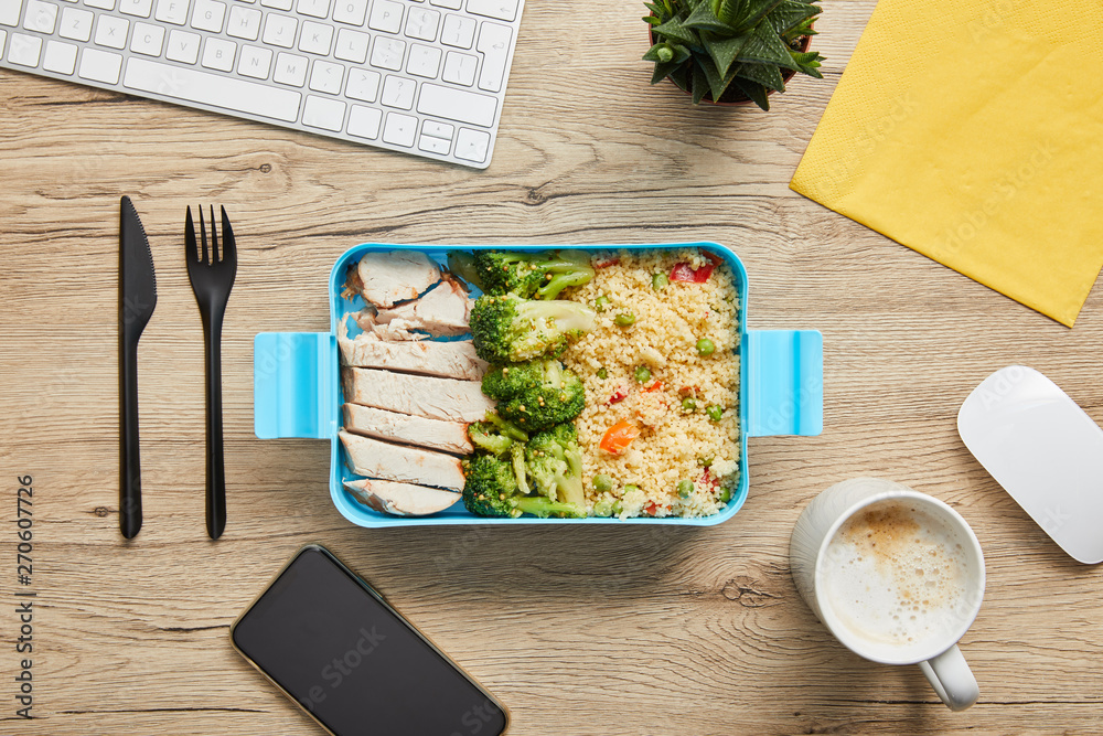 Top view of lunch box with chicken, broccoli and risotto on table with ...