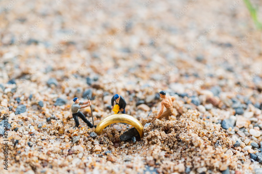Miniature people : worker team digging gold rings on the floor ...
