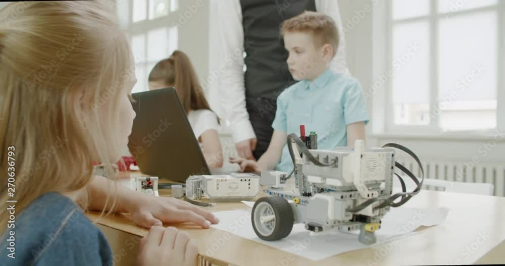 Curious kids working on a functional programable robot during robotics ...