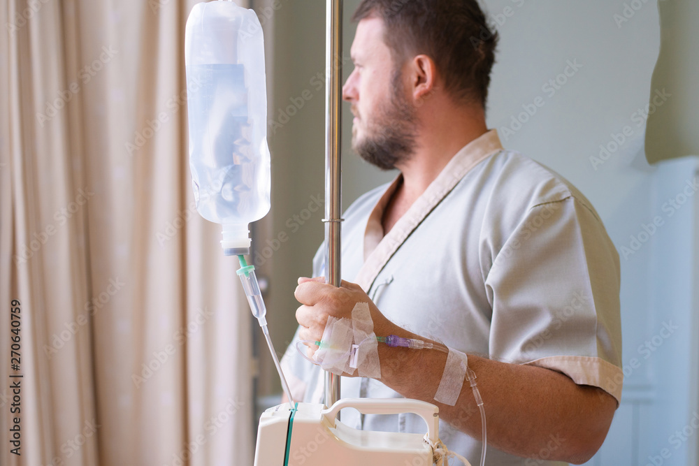 patient with a dropper looks out the window of the hospital room and ...