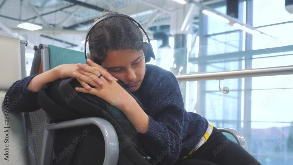 Tired girl teen in headphones traveler sleeping on the airport waiting ...