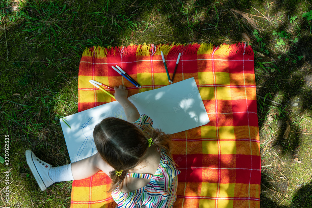 Little girl is painting with felt tip pens on the open air, Top view ...