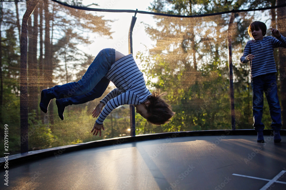 Sweet preteen boy jumping on trampoline making somersaults in the air ...