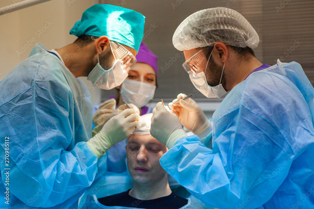 Baldness treatment. Hair transplant. Surgeons in the operating room ...