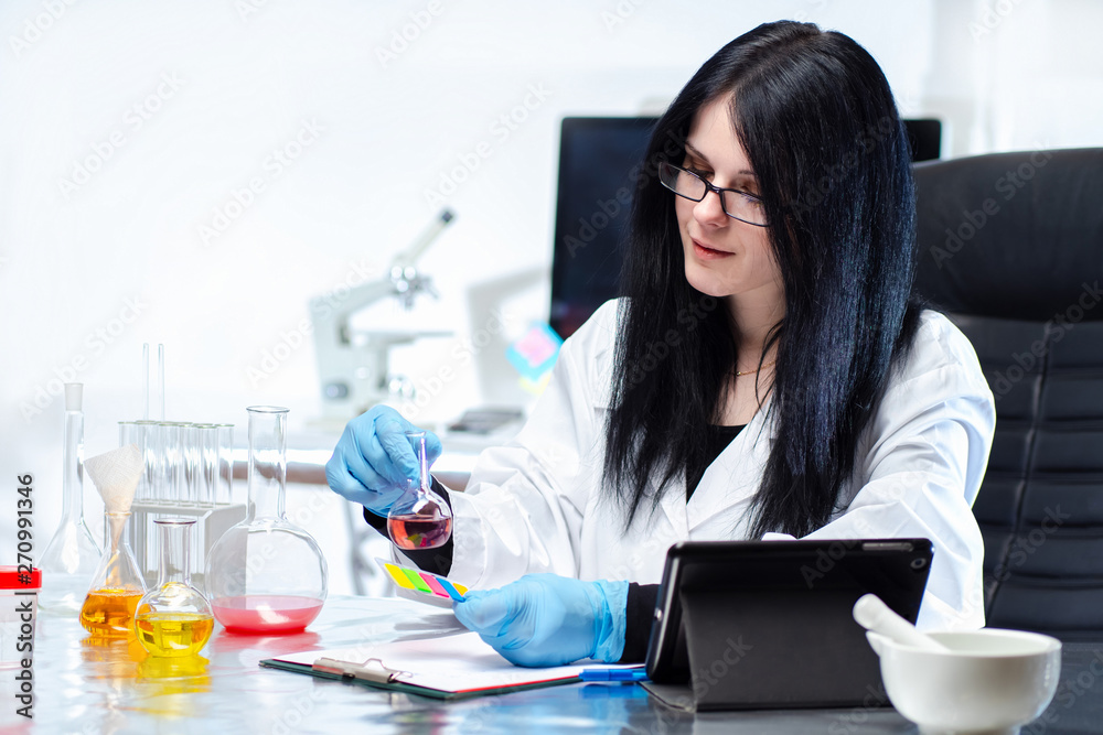 Chemical laboratory. Girl laboratory assistant observes a chemical ...