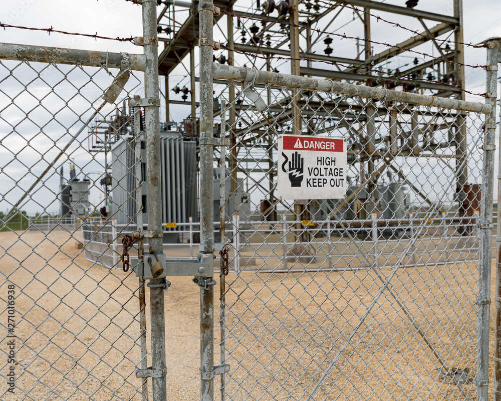 High voltage warning sign on locked gate surrounding an electrical ...