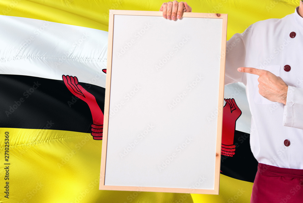 Bruneian Chef holding blank whiteboard menu on Brunei flag background ...