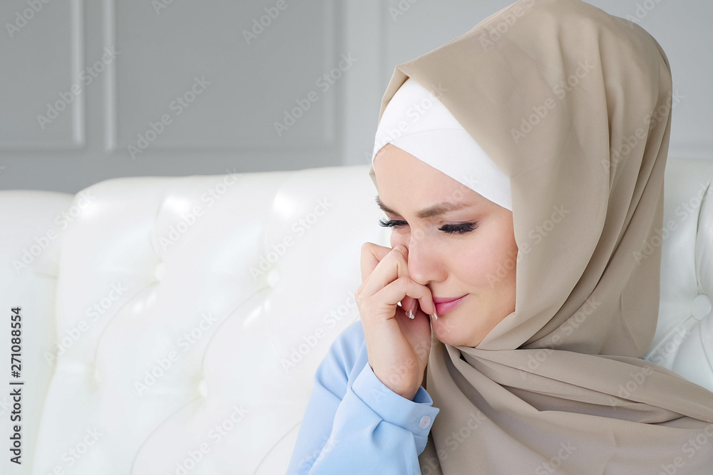 Portrait of beautiful young sad crying muslim woman in beige hijab is ...