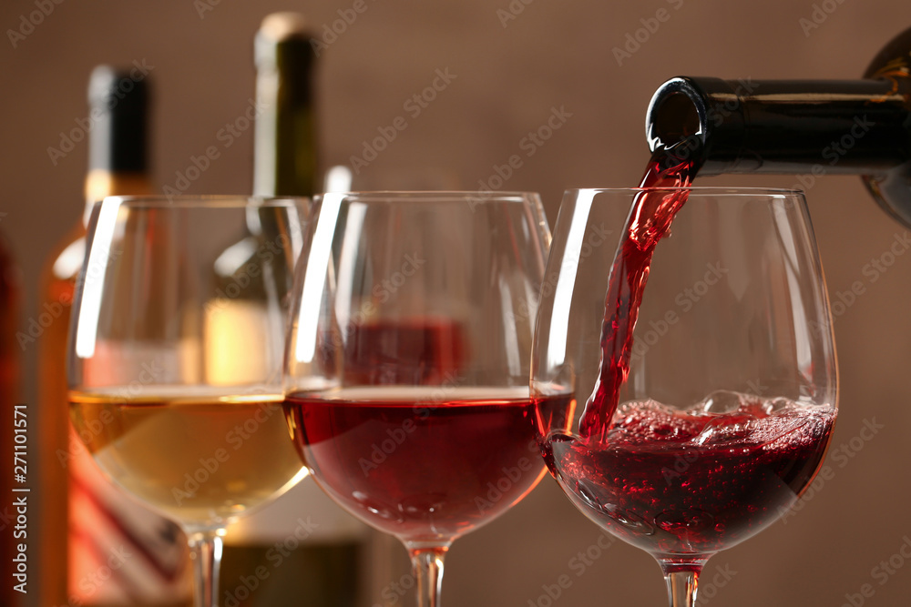 Pouring wine from bottle into glass on blurred background, closeup ...