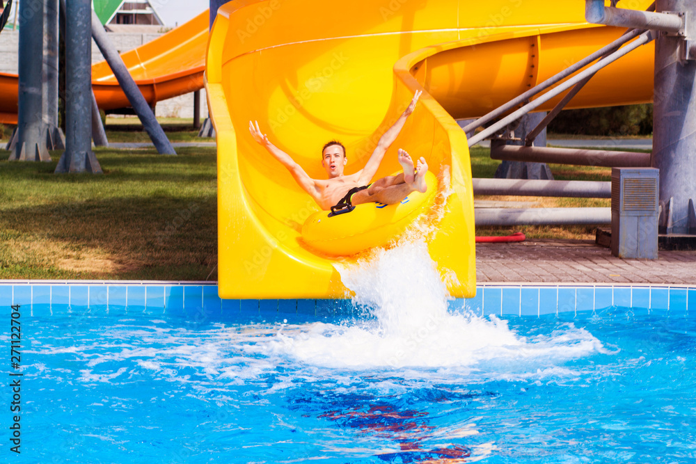 Funny excited man enjoying summer vacation in water park riding yellow ...