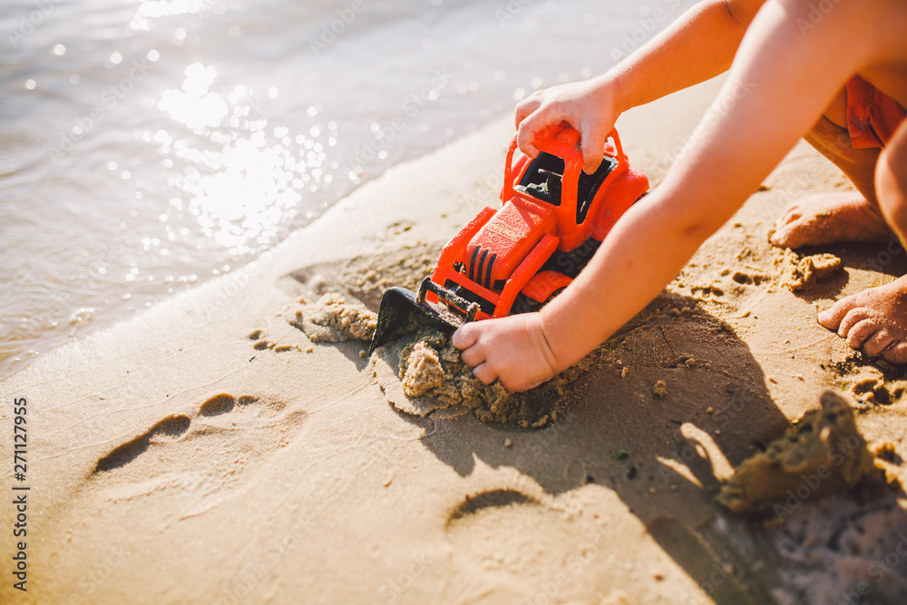 child boy playing on the beach near the river toy red tractor Stock ...