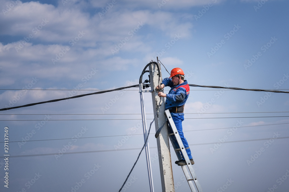 electrical engineer performs wiring on a high pole standing on the ...