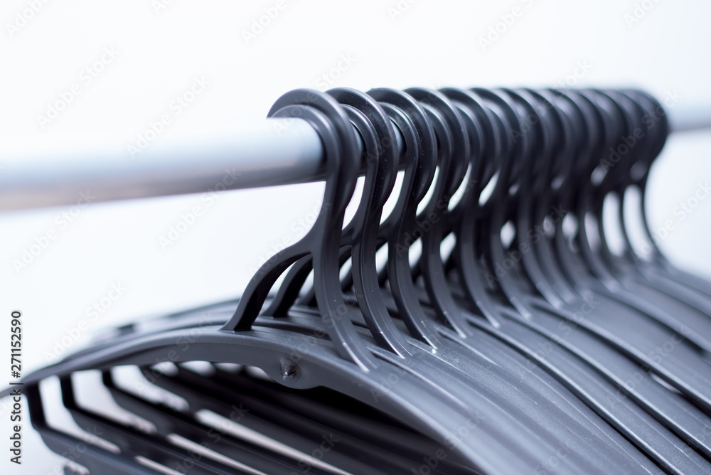 black plastic hangers hang on a light background. many different ...