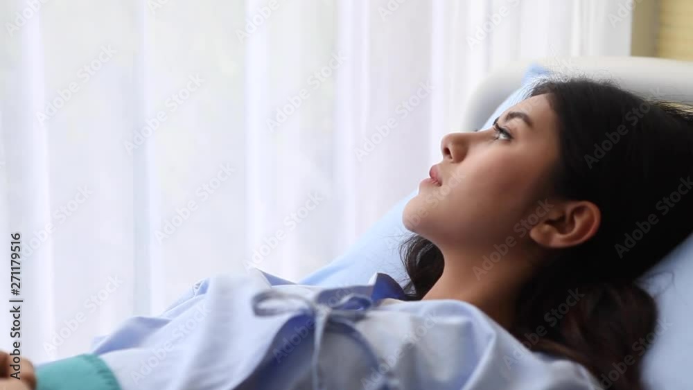female patient in hospital bed . Sad young woman laying down in ward ...