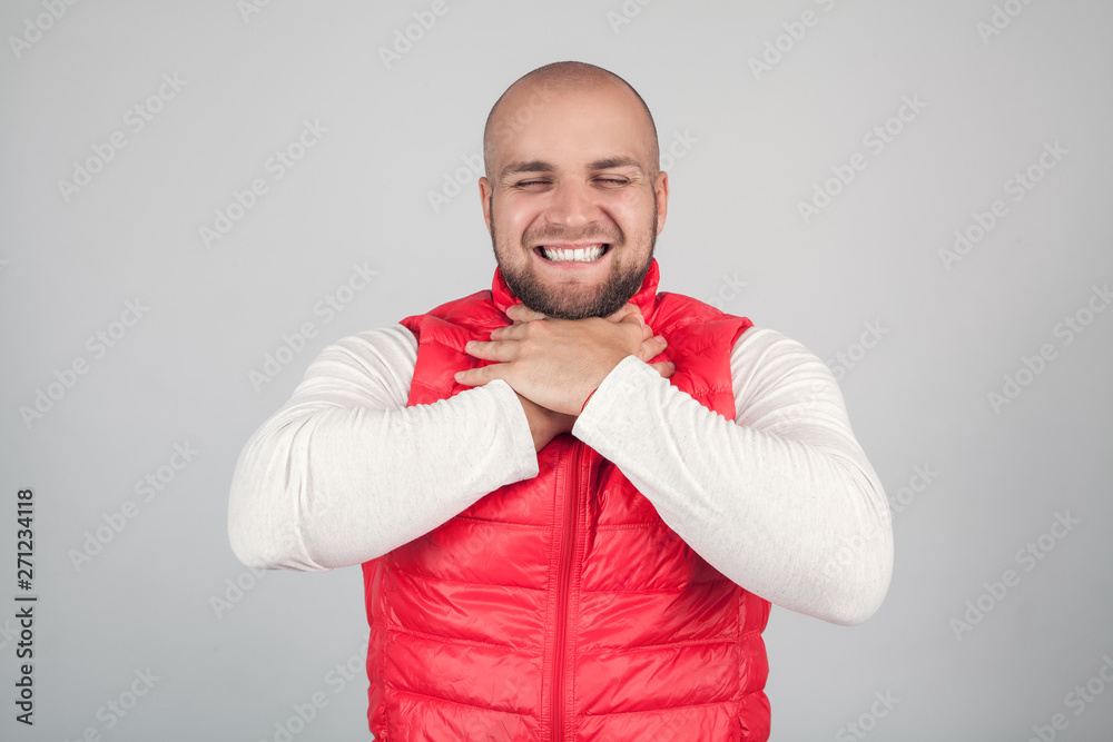 A young man with a thick beard and a bald-head holds his hands on his ...