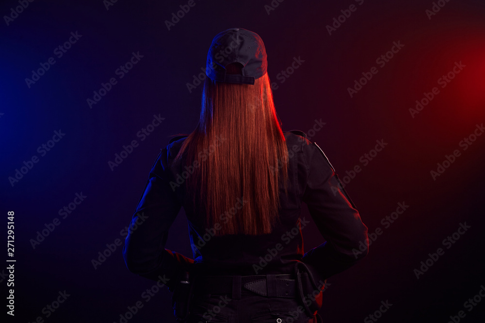 Serious female police officer is posing for the camera against a black ...