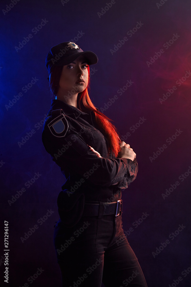 Serious female police officer is posing for the camera against a black ...
