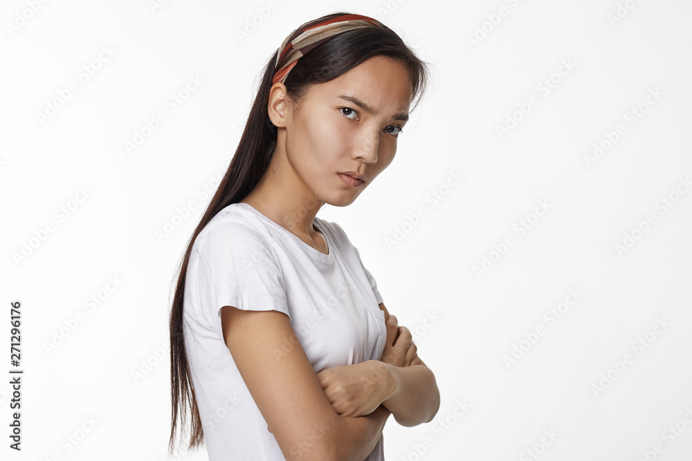 Grumpy dissatisfied young Chinese woman in white top frowning and ...